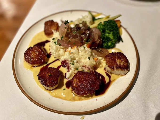 Perfectly seared scallops arranged like edible art, proving fine dining and historic charm make excellent dinner companions.