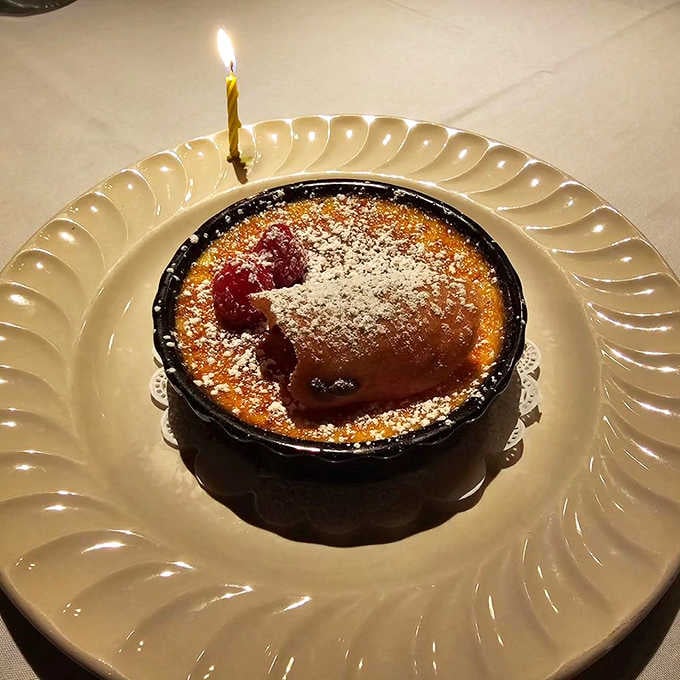 The bourbon cr&egrave;me br&ucirc;l&eacute;e arrives with a birthday candle, because some desserts deserve their own celebration and applause.