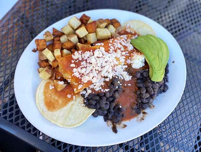 Huevos rancheros with black beans, potatoes, avocado, and crumbled cheese, this is breakfast done right.