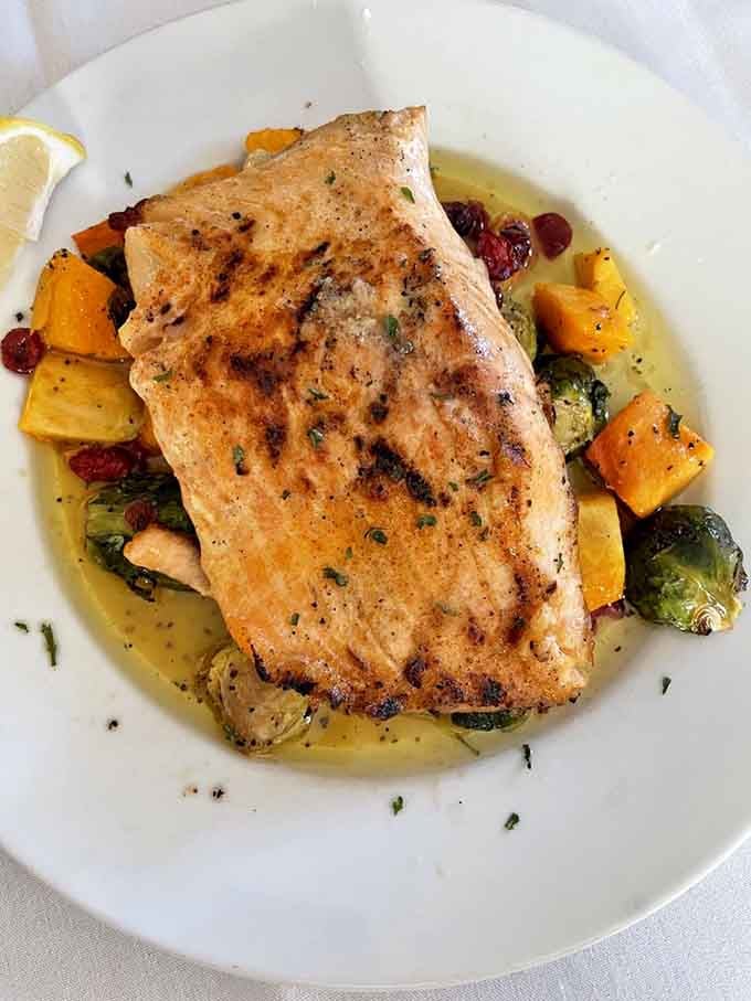 Perfectly grilled salmon sitting pretty on a bed of vegetables like it's posing for its yearbook photo.