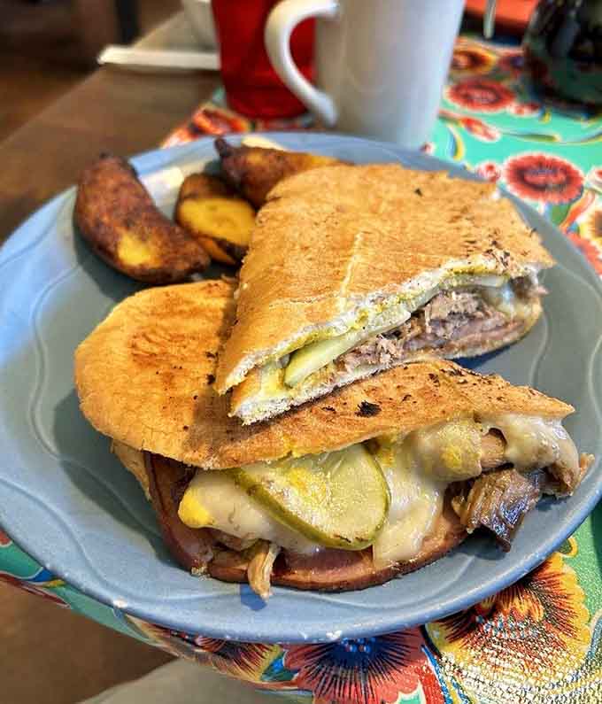 Behold the Cuban sandwich in all its pressed, melty glory, flanked by golden plantains that deserve their own fan club.