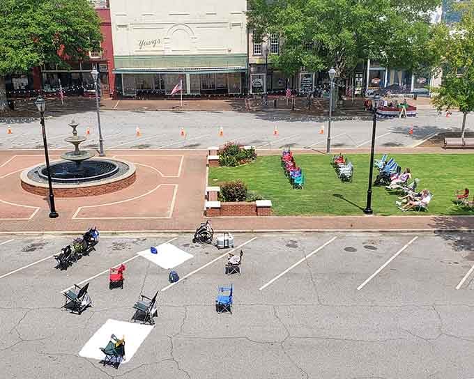 The town square transforms into an outdoor living room where neighbors gather like it's still 1955, fountain and all.
