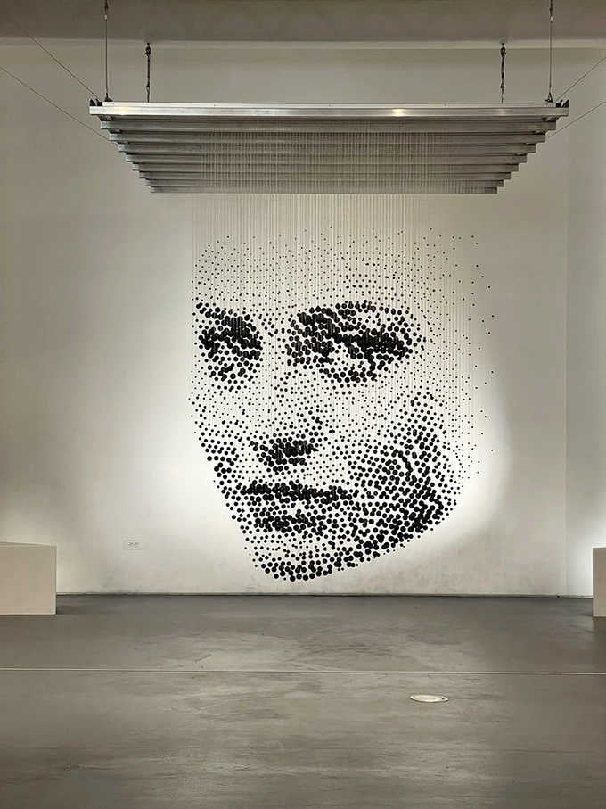 Thousands of suspended dots create a haunting face that seems to watch you from every angle.