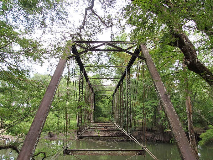 This rusty bridge stretching across dark waters feels like the opening scene from every Southern ghost story ever told.