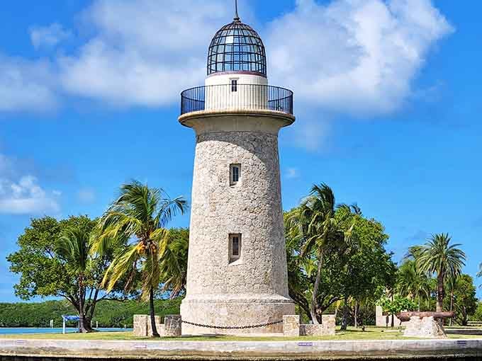 Coral rock and a sparkling glass dome create a lighthouse that's part tropical dream, part architectural whimsy under blue skies.