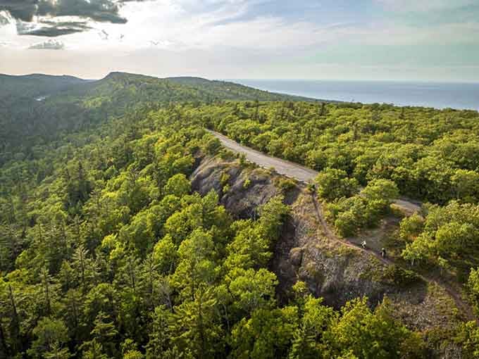 From this bird's-eye view, the winding road cuts through endless forest like a thread stitching earth to sky.