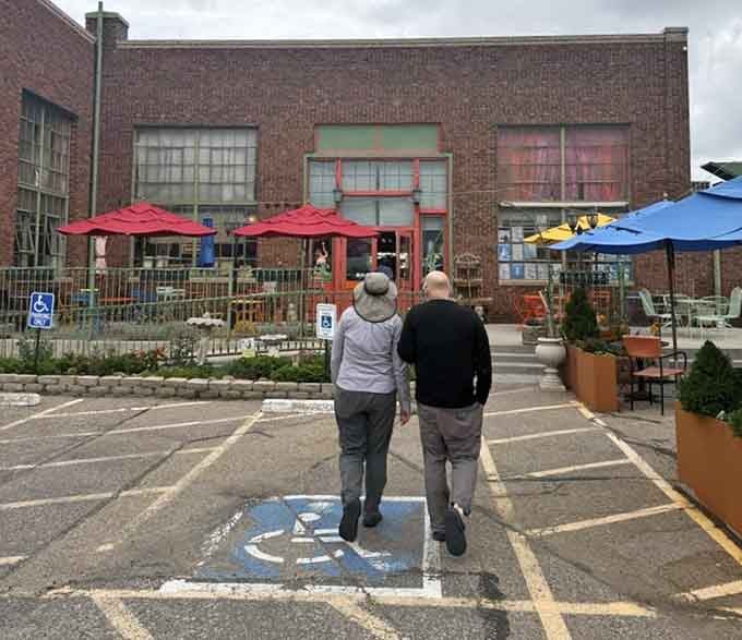 Two friends approach colorful umbrellas and brick walls that whisper stories of artisan cheese and Old World craftsmanship inside.