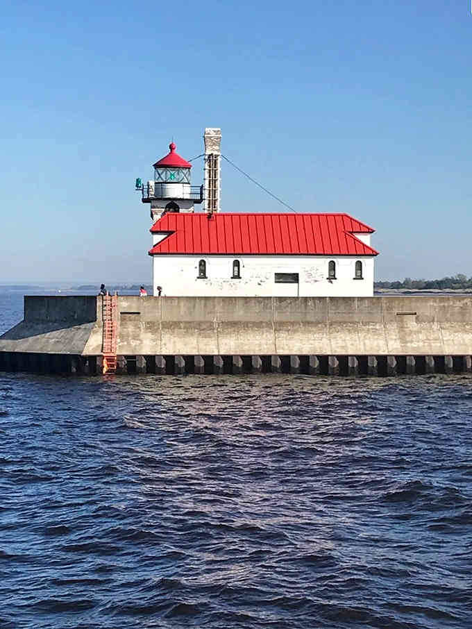 That cheerful red roof pops against white walls like a peppermint candy, guiding massive freighters through Duluth's busy channel.