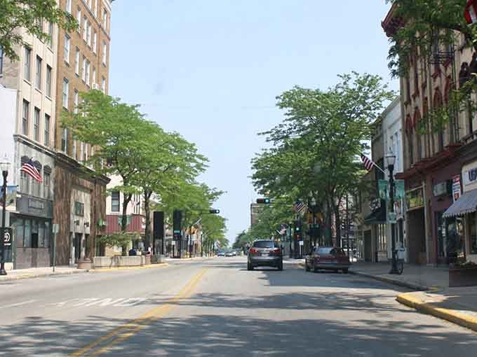 Your sunny afternoon stroll through historic Fond du Lac offers charming architecture, leafy green trees, and a peaceful, welcoming atmosphere.