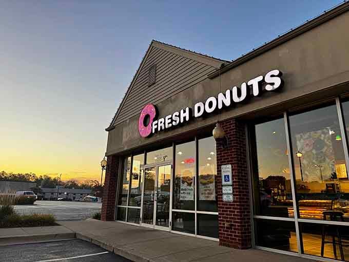 Golden hour hits this storefront just right, making that pink donut logo glow like a beacon for anyone craving something sweet.