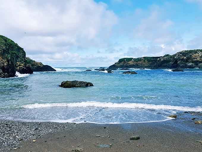 Rocky outcrops frame this wild beach where waves crash with the enthusiasm of a standing ovation.