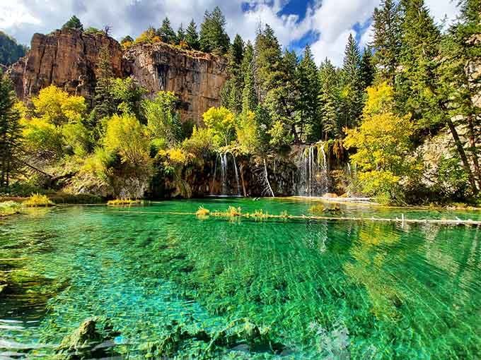 Emerald water so clear you can see straight through to the bottom, framed by golden aspens.