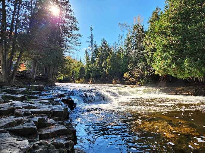 Sunlight dances across the wide cascade, creating a sparkling curtain of water perfect for summer wading.