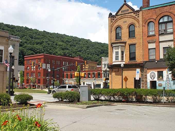 Red brick buildings catch golden light against green mountains in a scene that belongs on a jigsaw puzzle.