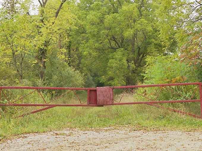 That rusty gate blocking the dirt road practically screams "turn back now" in the most polite way possible.