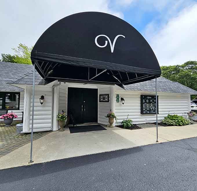 The elegant black awning with its distinctive monogram hints at the refined dining experience waiting just beyond those doors.