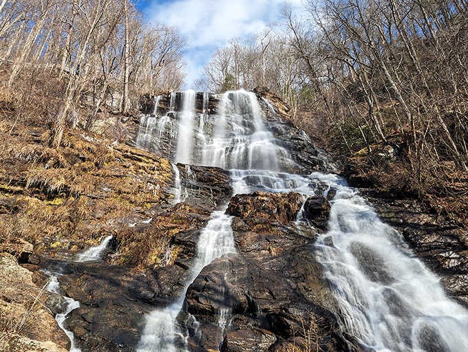 Winter reveals the waterfall's raw power, with bare trees standing like witnesses to this eternal mountain performance.