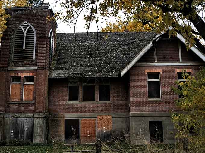 Nature slowly reclaims this abandoned building, wrapping it in shadows and stories from another era's Sunday mornings.