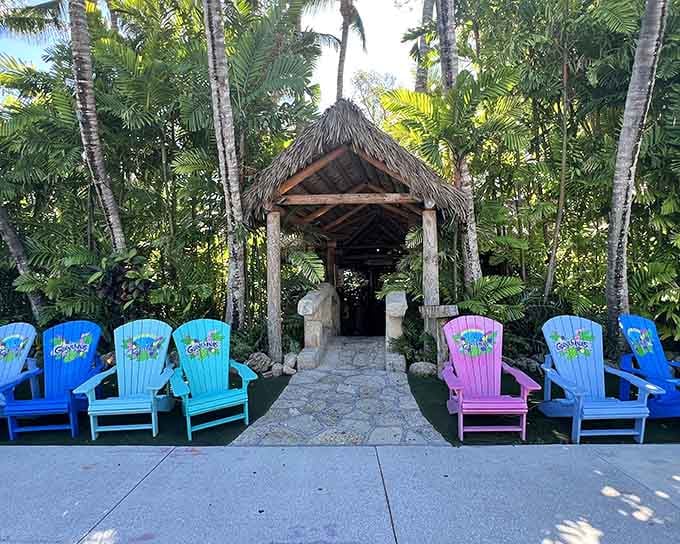 Colorful Adirondack chairs circle a thatched-roof hut like a tropical version of gathering around the campfire for stories.
