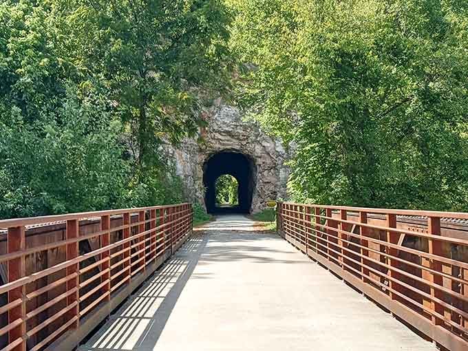 The modern bridge leading to this carved rock passage proves old railroad engineering still impresses in our smartphone era.