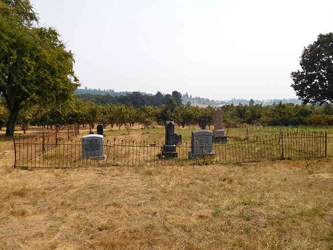 Iron fences protect these historic graves while golden grass and distant hills frame a cemetery that's witnessed Oregon's entire modern history.