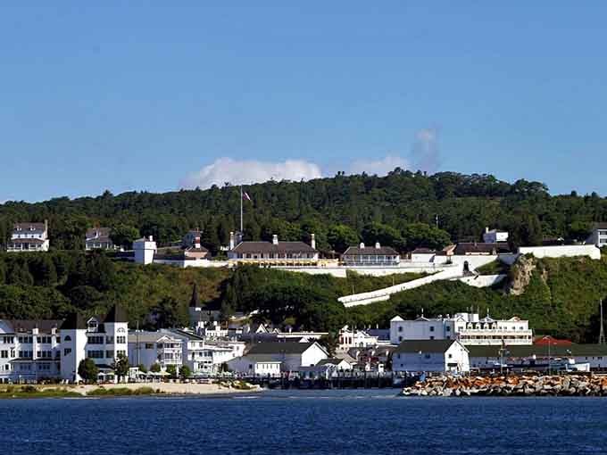 The historic fort crowns the hillside above charming white buildings clustered along the rocky shoreline below.