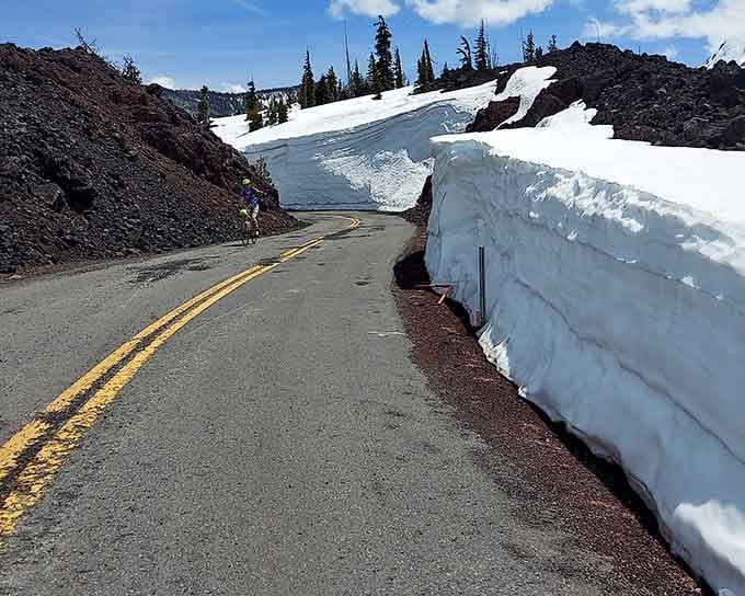 Towering snow walls flank the road like frozen sentinels guarding the passage through volcanic terrain.