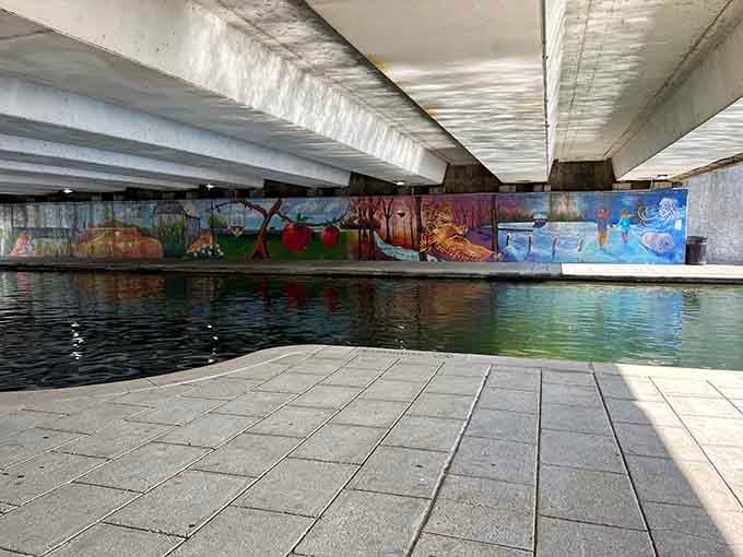 Vibrant murals transform ordinary concrete into storytelling canvases, bringing color and life to this unique urban waterway space.