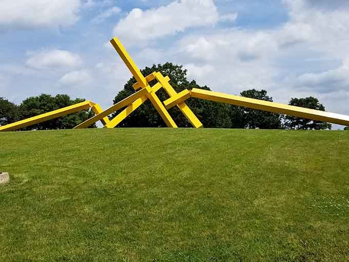 Bright yellow beams twist and intersect across green grass creating a striking conversation between color and form.