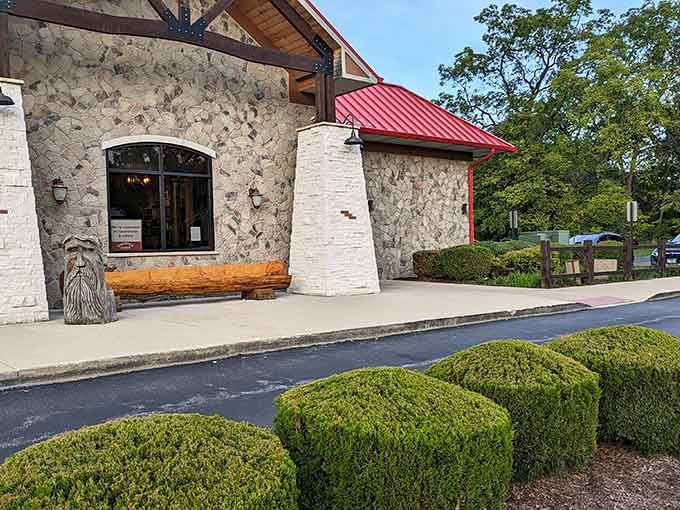 Manicured hedges meet rustic charm where that carved wooden bear stands guard like a friendly bouncer.