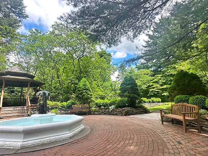 A peaceful fountain anchors this brick courtyard, surrounded by mature trees that have witnessed decades of garden transformations.