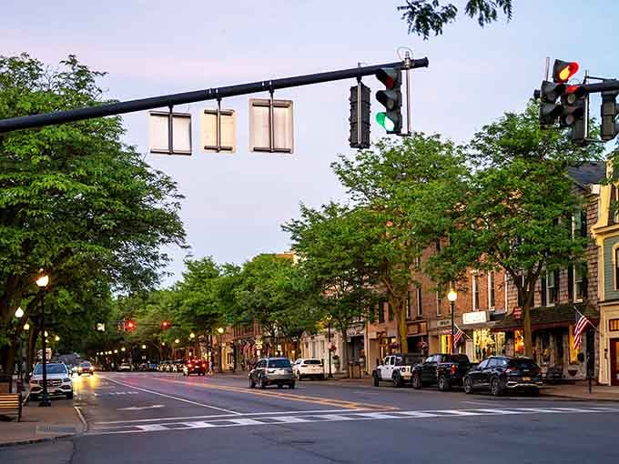 Main street comes alive as evening descends, with historic buildings glowing warmly under charming vintage-style street lamps.