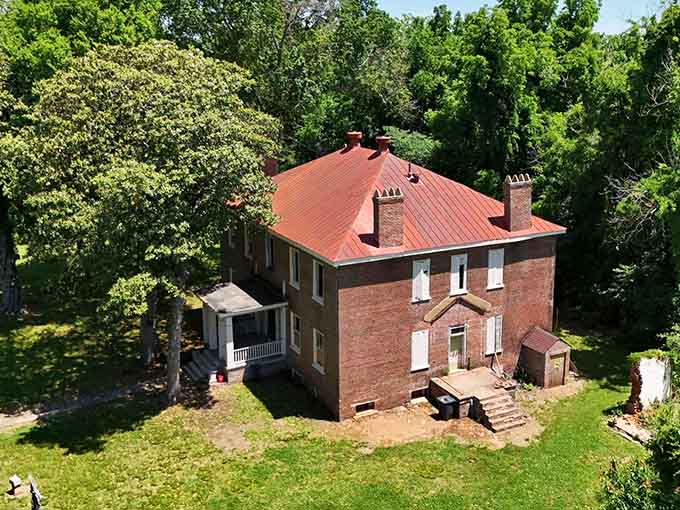 The red roof catches sunlight while overgrown grounds hint at the elegant parties this place once hosted.