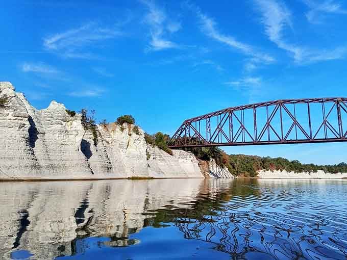 The layered white walls reflect perfectly in the calm water, doubling the drama like nature installed its own mirror.