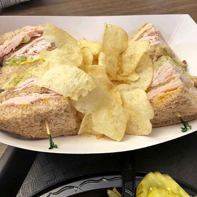 The turkey club sandwich arrives stacked high with chips, proving that sometimes the best things come in triple-decker packages.