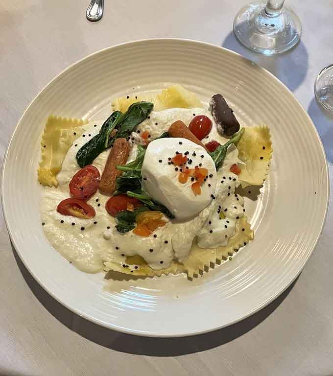 Burrata-topped ravioli with fresh tomatoes and greens, proving Italian cuisine feels right at home in any castle.