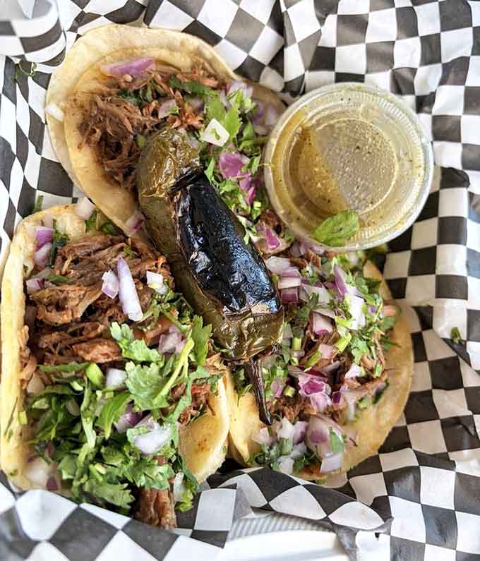 Crispy tortillas loaded with birria, topped with fresh cilantro and onions, plus that essential dipping cup of liquid gold.