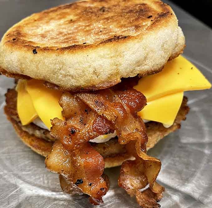 Bacon cascading off a breakfast sandwich like a delicious waterfall, because mornings deserve this kind of drama.