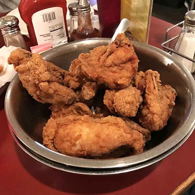 Golden fried chicken piled high in a metal bowl, proving that sometimes simple perfection needs no introduction.