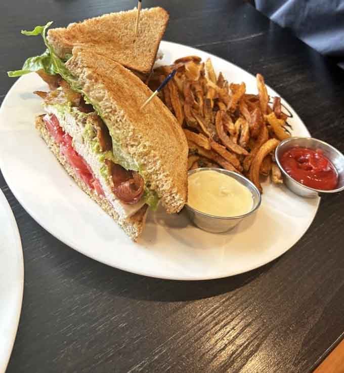 The turkey club arrives stacked higher than your weekend plans, with sweet potato fries standing guard like delicious sentries.