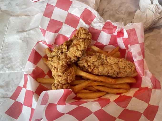 Golden fried chicken tenders rest on their fries like they're posing for their close-up in a Norman Rockwell painting.