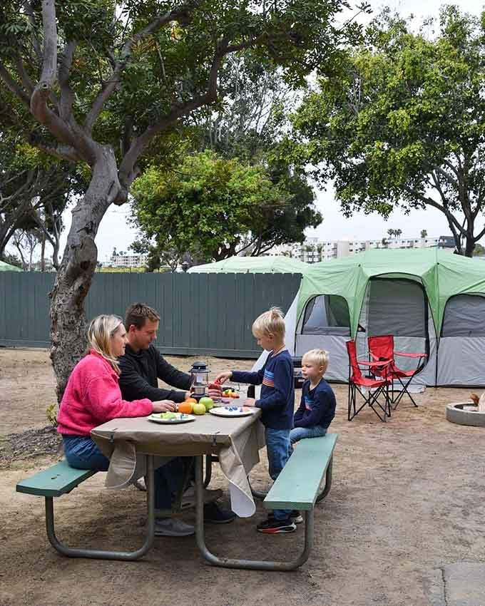 Families gather around picnic tables at their campsites, creating memories one meal at a time.