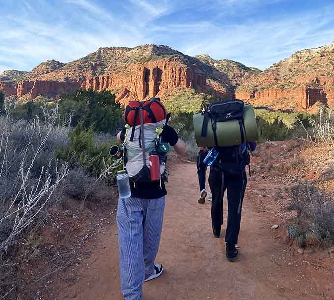 Backpackers heading into the canyons, carrying everything they need except maybe a reasonable explanation for their life choices.