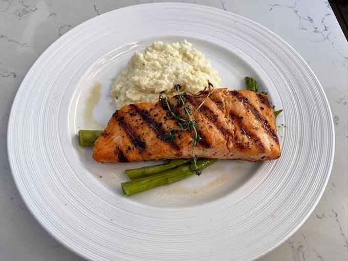 Perfectly grilled salmon with those beautiful char marks sits atop crisp asparagus like it's posing for its close-up.