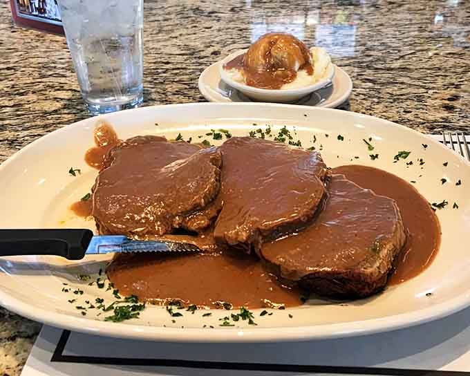 Three perfect slices of meatloaf swimming in rich gravy, proving that simple done right beats fancy done wrong.