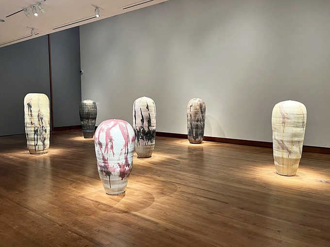 Translucent vessels stand like sentries in the gallery, their ghostly forms capturing light like bottled moonbeams.