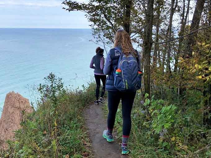 The trail beckons hikers forward through peaceful woodland, building anticipation before revealing the spectacular geological drama ahead.