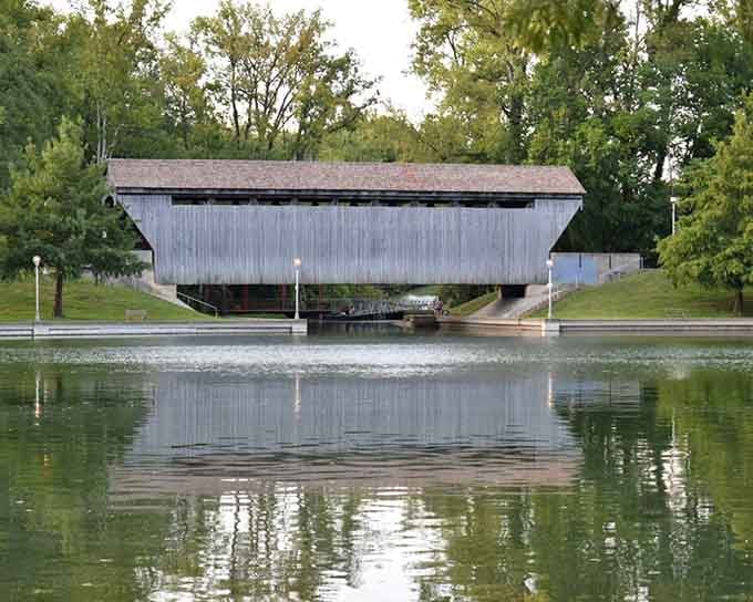 The covered bridge at Mill Race Park reflects perfectly, like it's admiring its own timeless design.