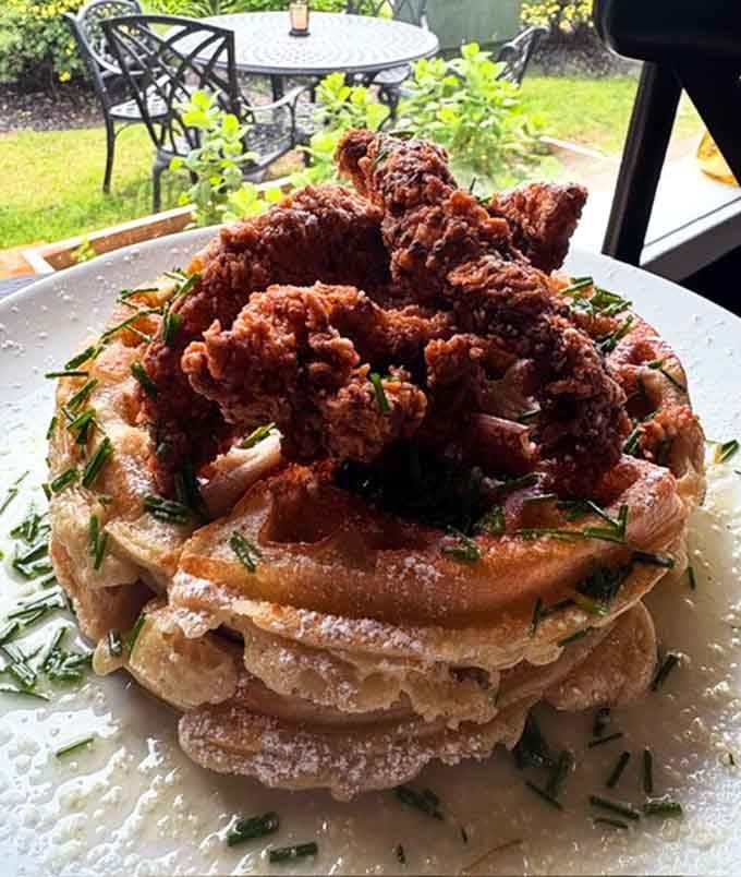 Chicken and waffles stacked so high it defies both gravity and common sense, proving that sometimes excess is absolutely necessary.