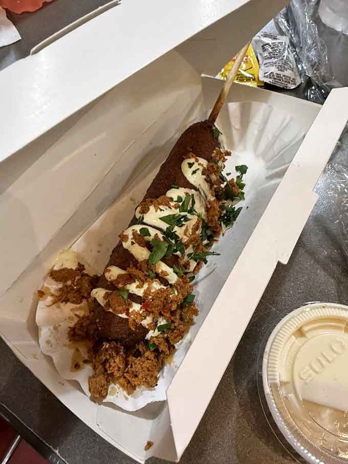 Sweet potato battered perfection topped with what appears to be heaven's own condiments, proving innovation belongs on sticks too.